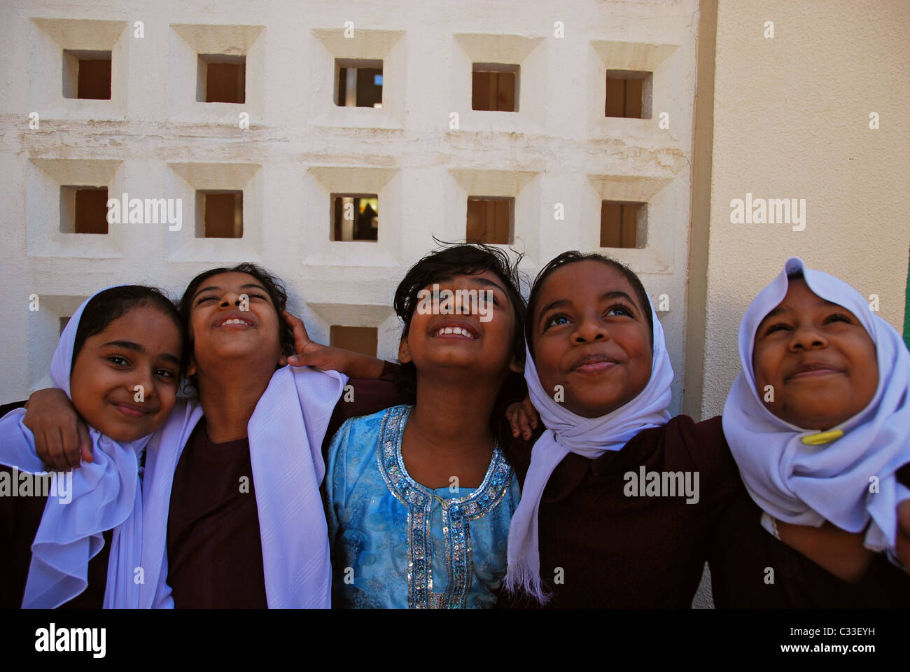 Oman, Muscat, close-up of happy five school girls with arms around in a ...