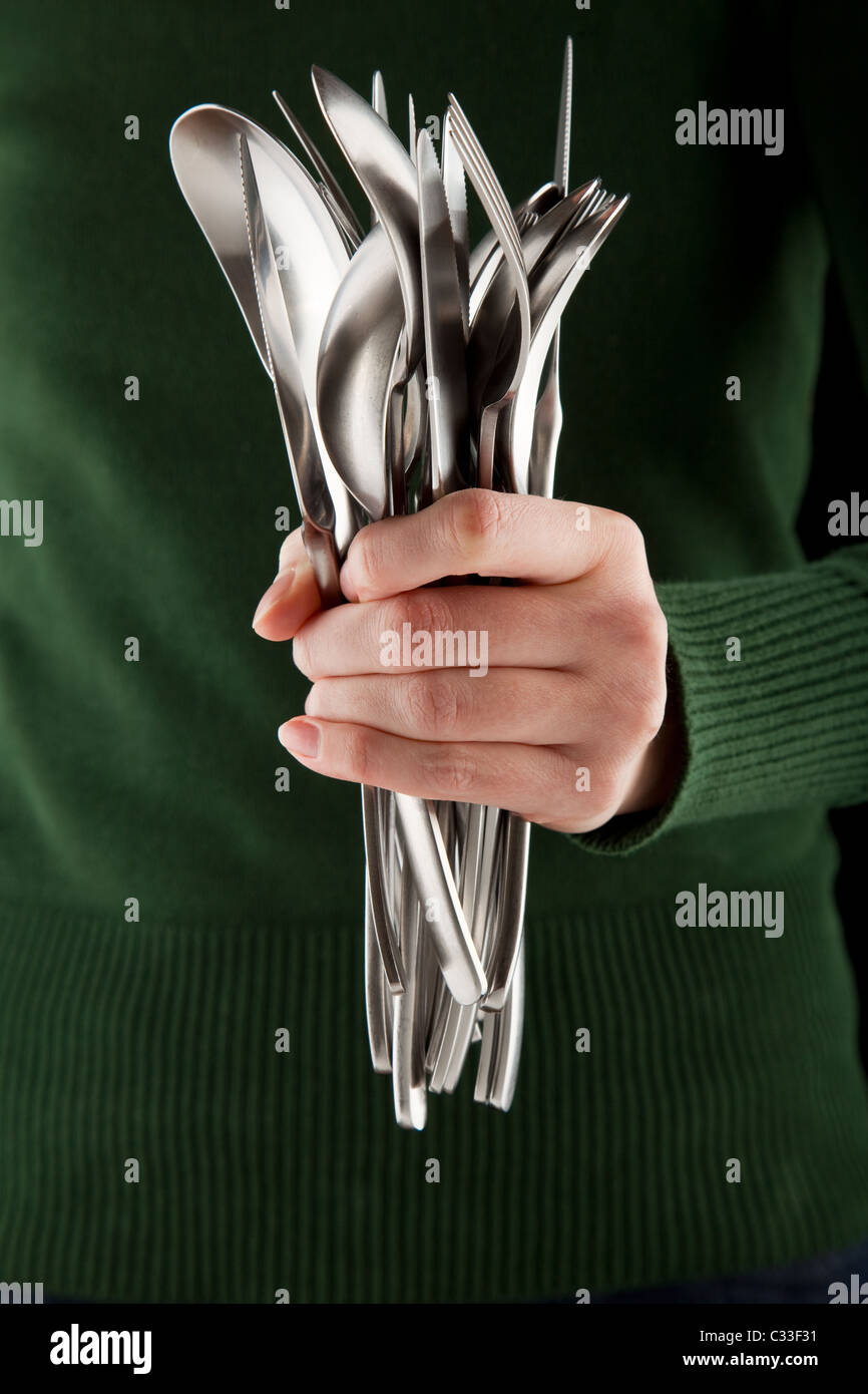 woman in a green jumper holds a bunch of silverware in her hand Stock ...