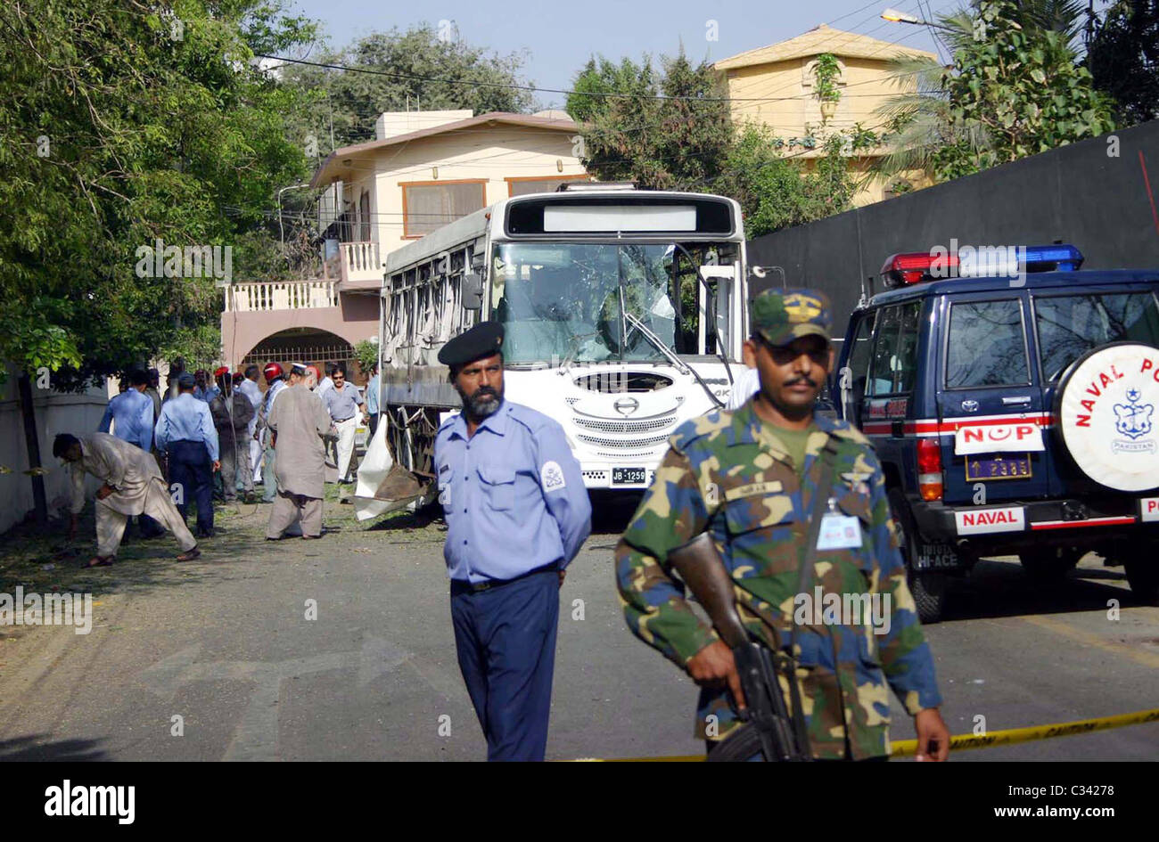 An army soldier stands alert in front of a damaged bus which was ...