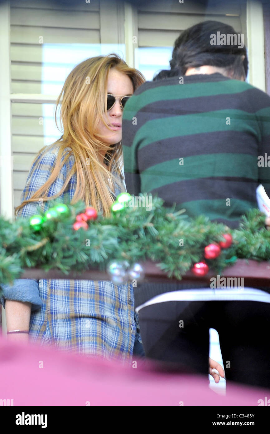 Lindsay Lohan smoking a cigarette with a friend on a private balcony ...