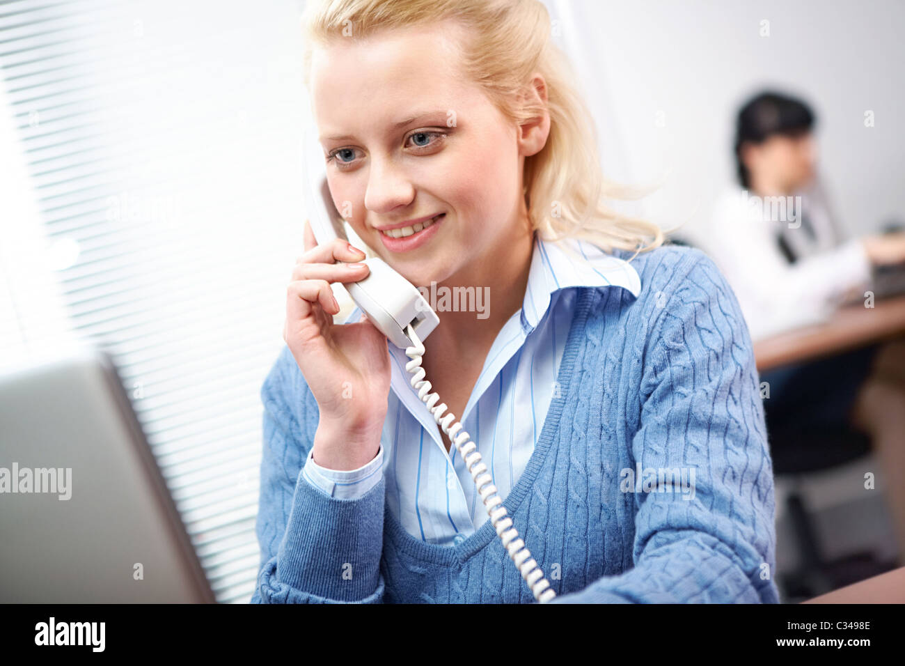 A young woman receptionist with a telephone receiver Stock Photo - Alamy
