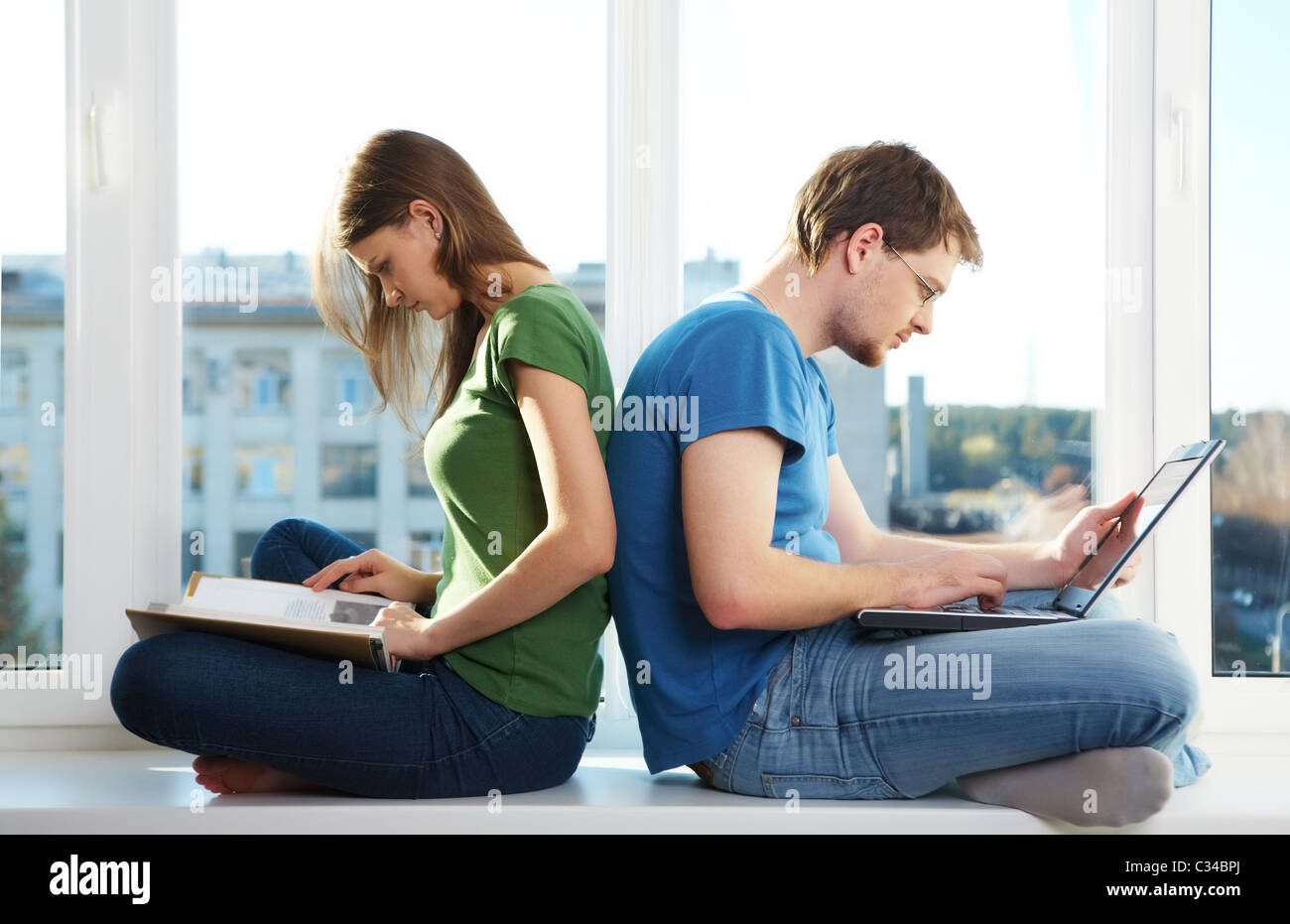 Photo of man and woman sitting back to back and doing their works Stock ...