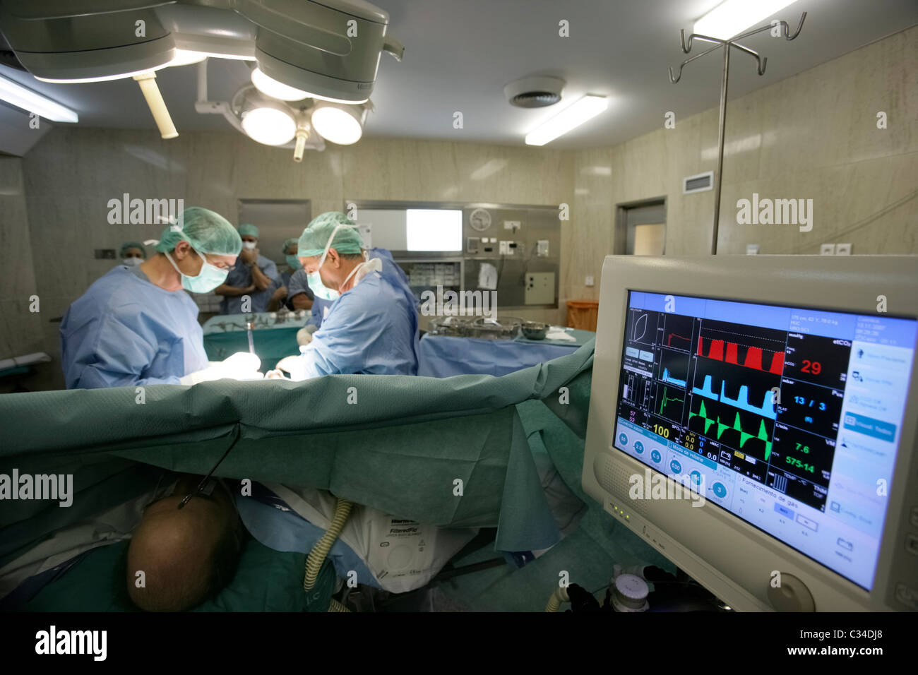 Wide angle view of vital signs monitor as doctors perform surgery in ...