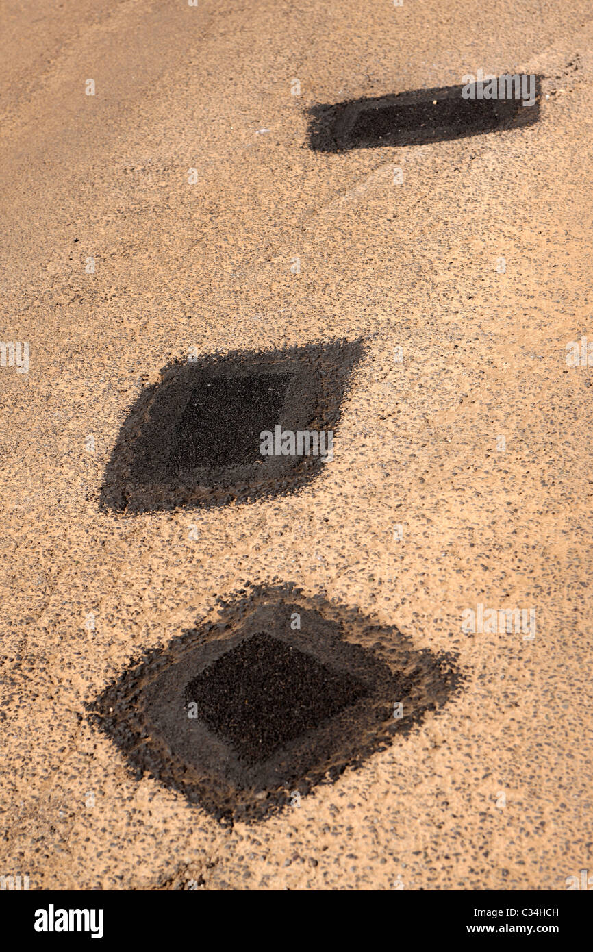 Patched up pot holes in a road Stock Photo - Alamy