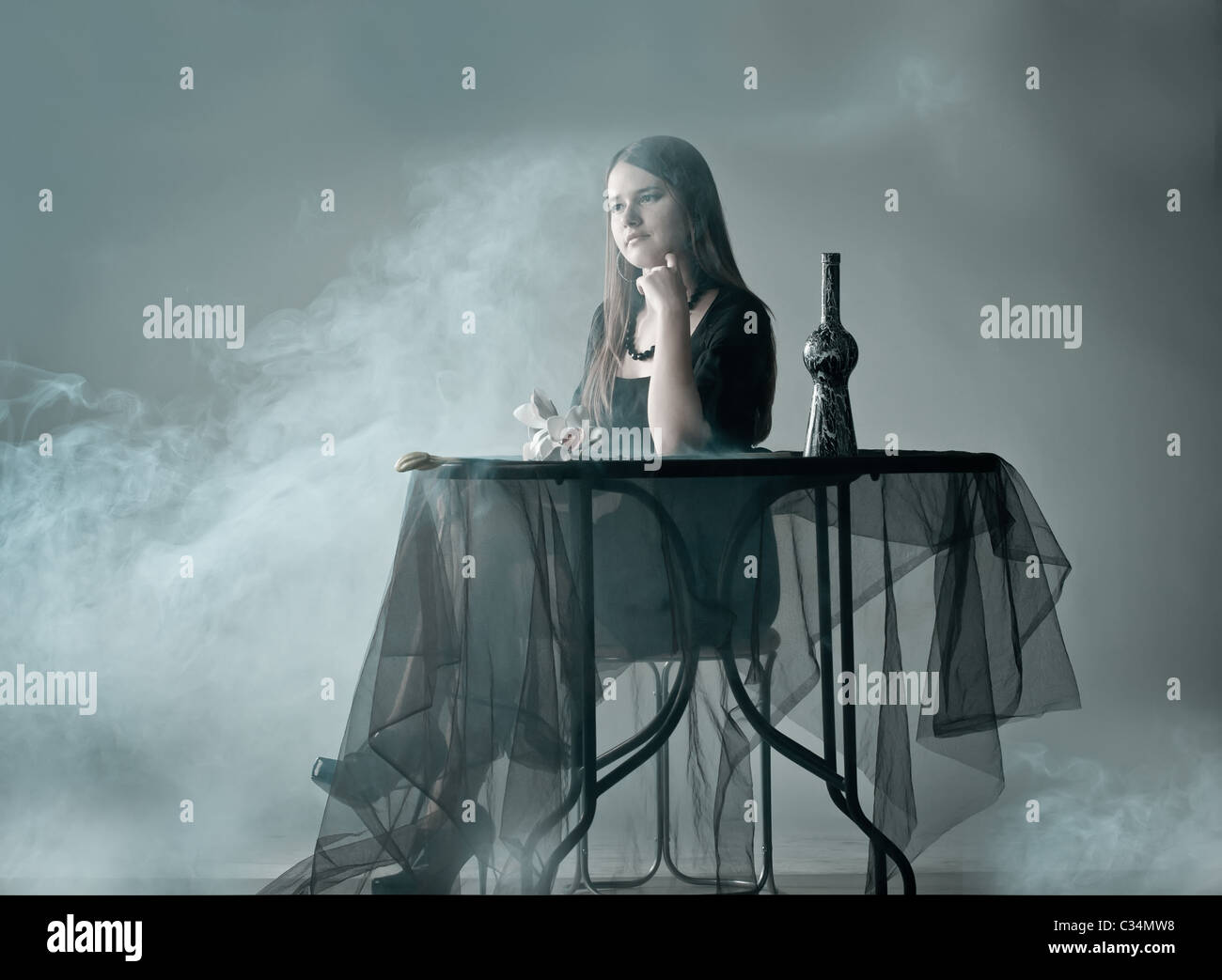 Woman sitting behind table in smoke Stock Photo - Alamy