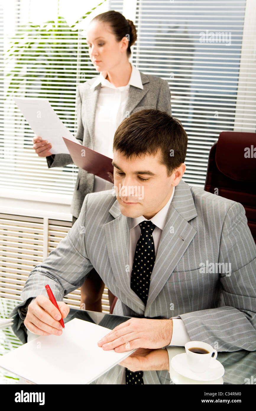 Portrait of serious boss signing contract with executive secretary on ...