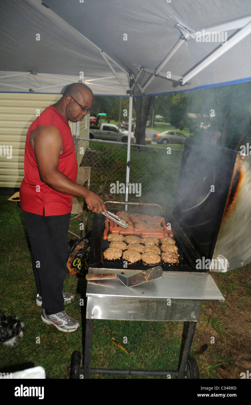 man barbecuing hot dogs and hamburgers at a cookout in Bowie, Maryland ...