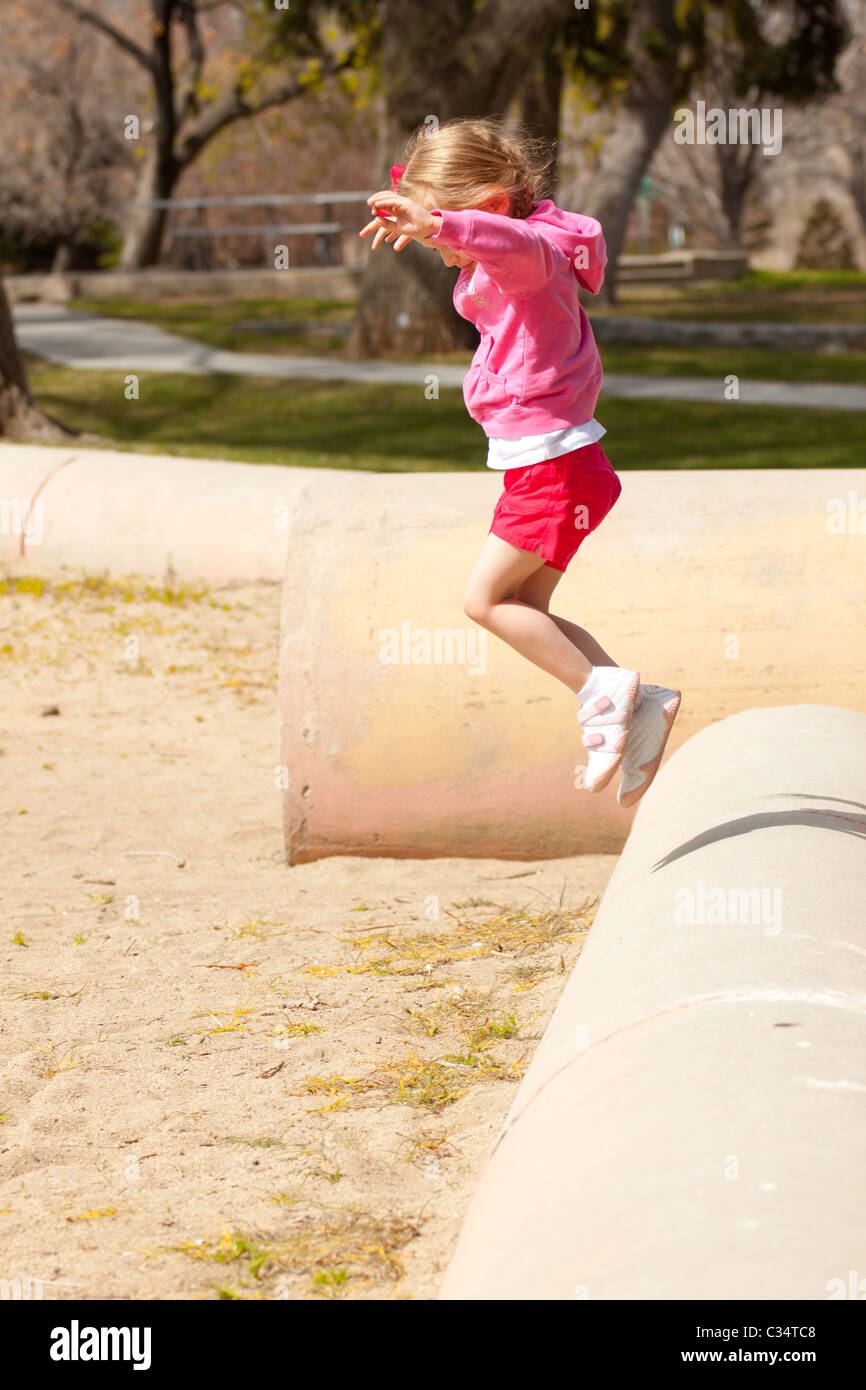 A great photograph of a young child jumping off of a concrete pipe in ...