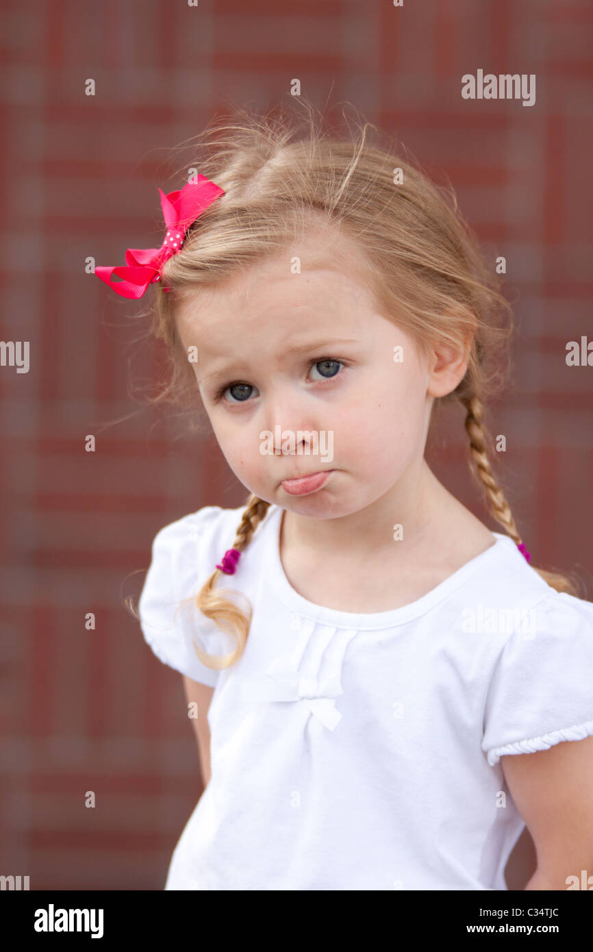 A girl pouting in front of a brick background Stock Photo - Alamy