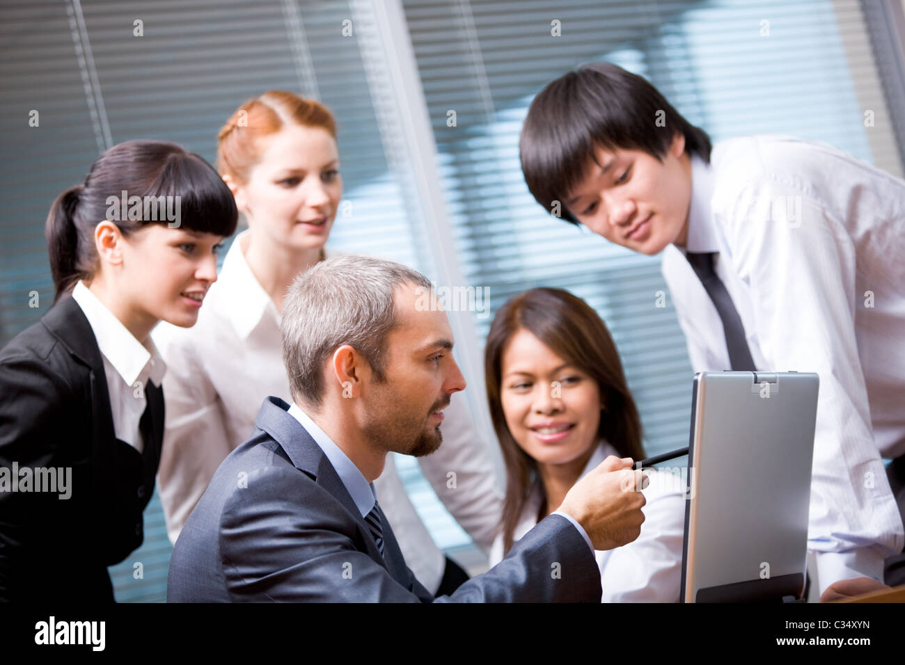 Portrait of executive employees looking at laptop monitor in office and ...