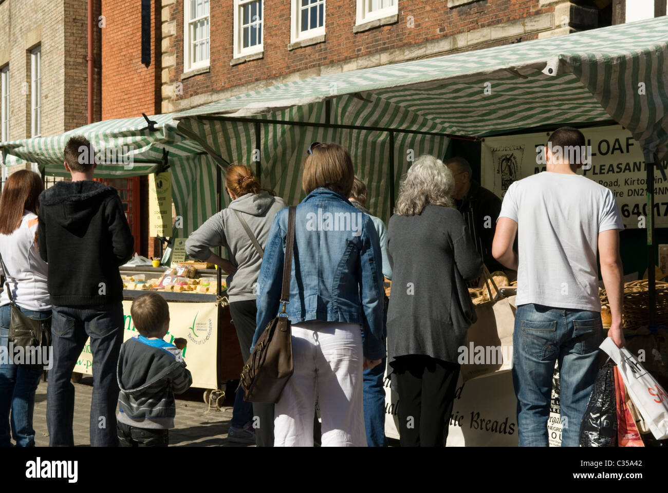 People queue at for Artisan bread and cheeses at a market stall ...