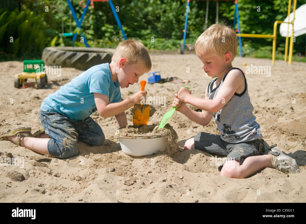 Two boys playing in the sandbox Stock Photo - Alamy