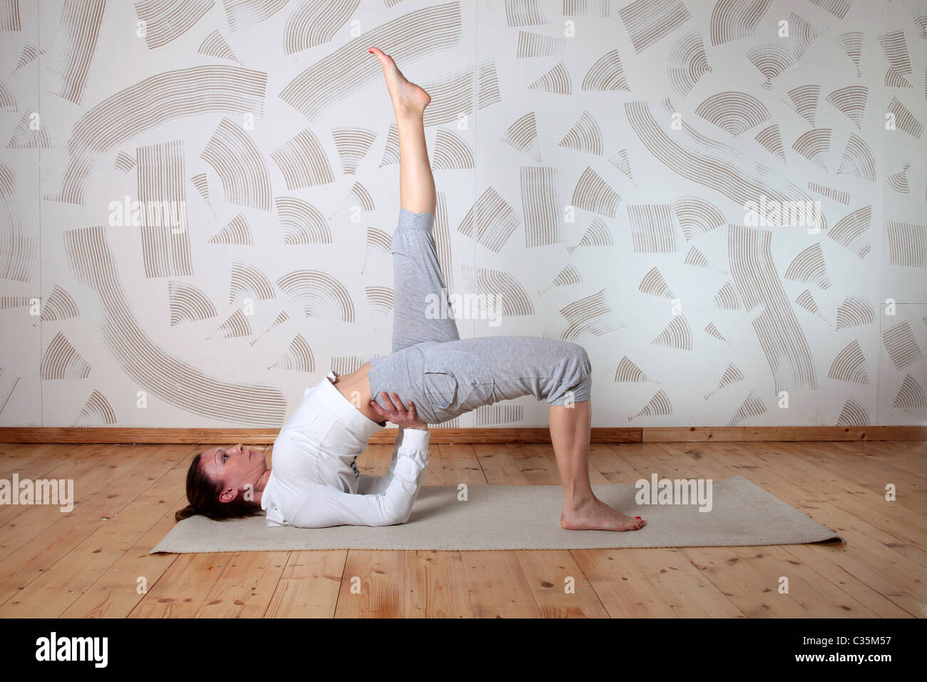 Woman during yoga exercise at a yoga body posture with candles around ...