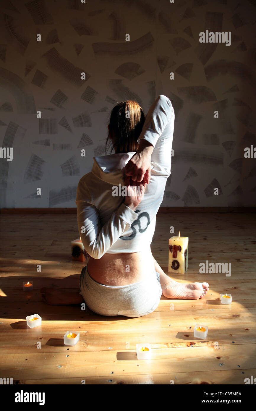 Woman during yoga exercise at a yoga body posture with candles around ...