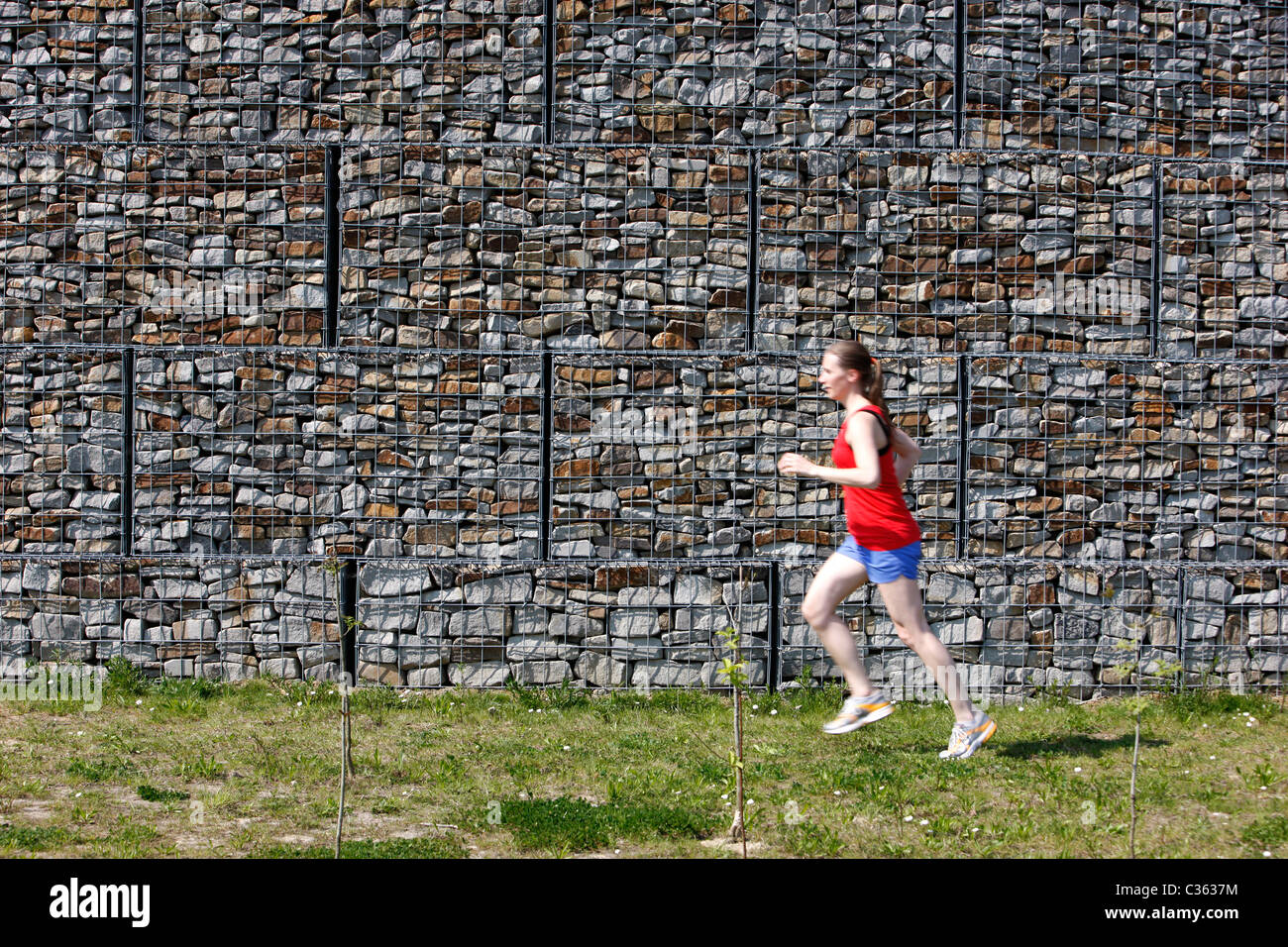 Female runner, in a public park, jogging in front of a stone wall Stock ...