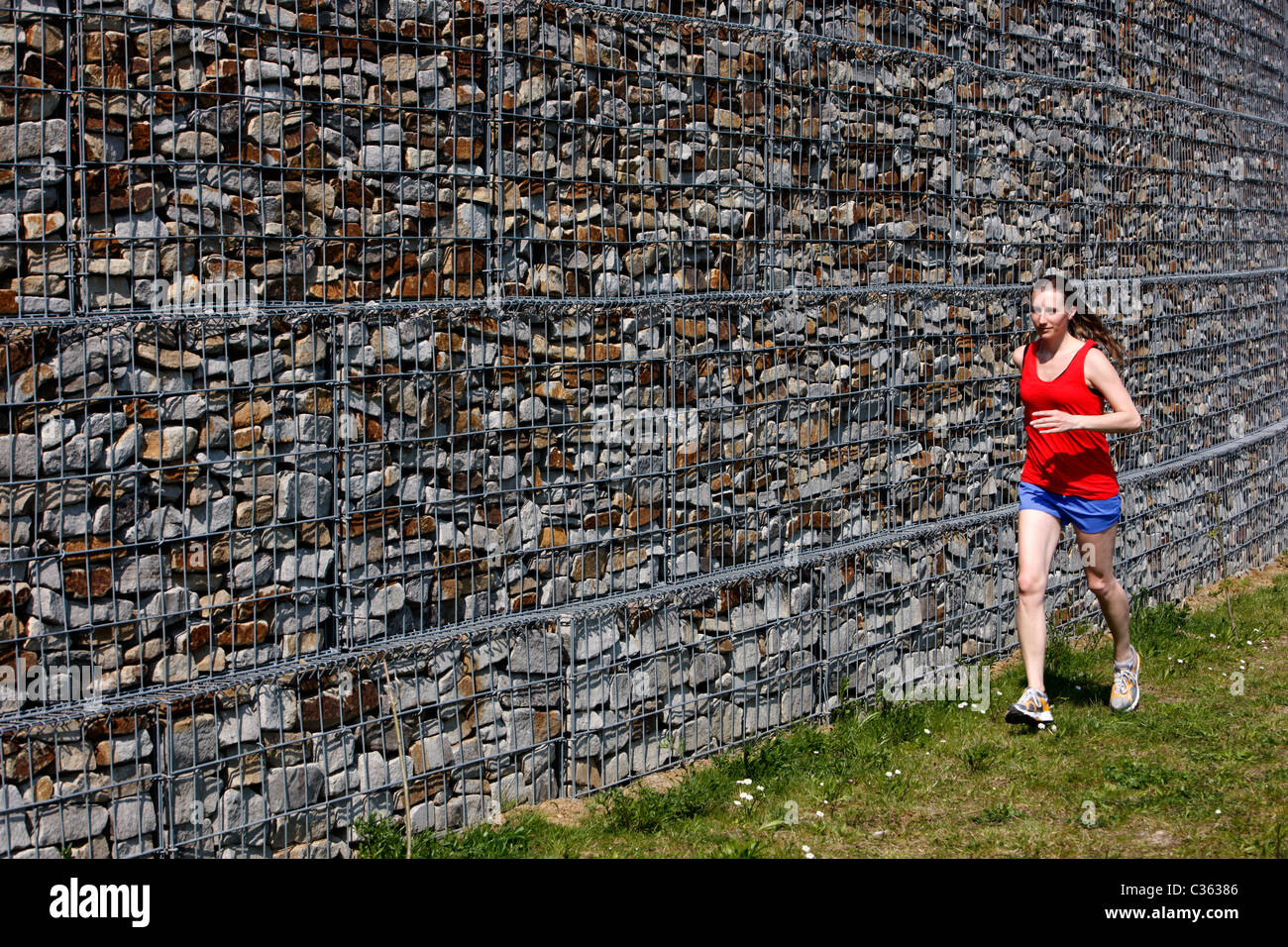 Female runner, in a public park, jogging in front of a stone wall Stock ...