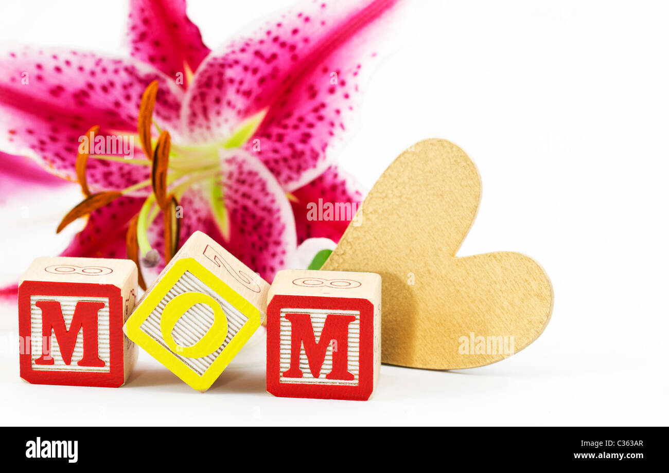 Gold heart and alphabet block letters spelling MOM are placed in front ...