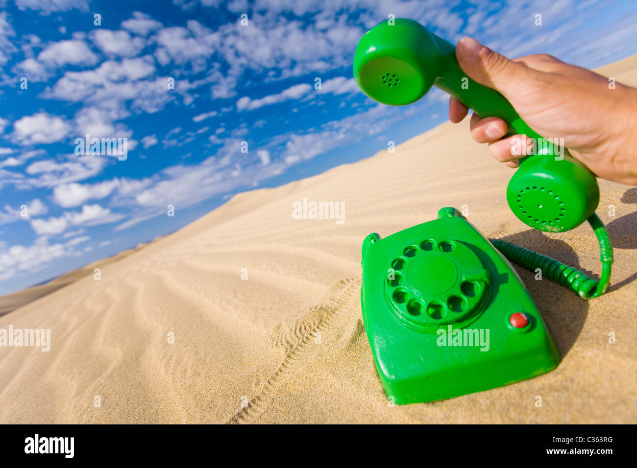 Hand answering an old-fashioned green telephone in the desert Stock ...