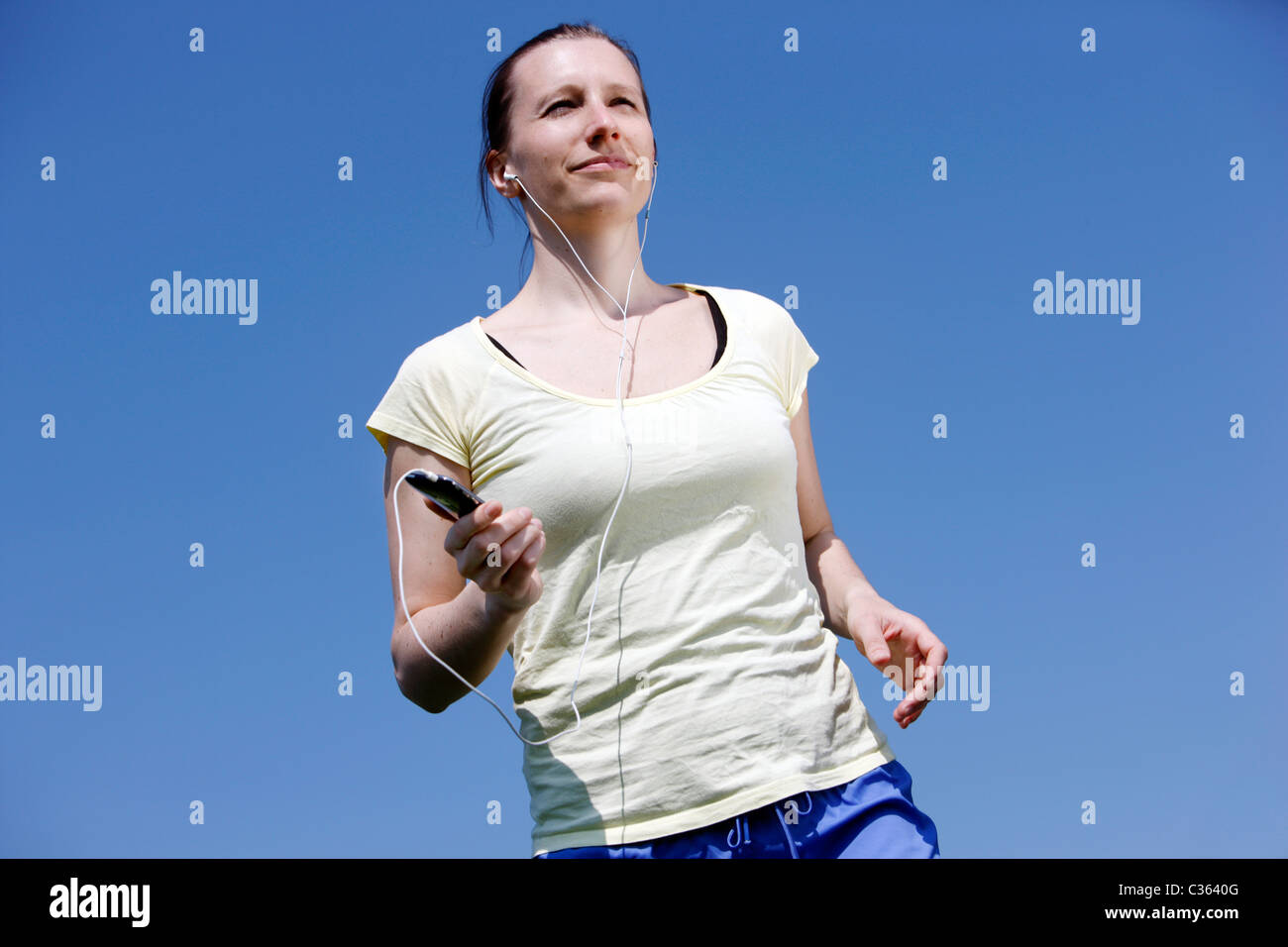 Female hobby runners, listening to music via earphones while jogging ...
