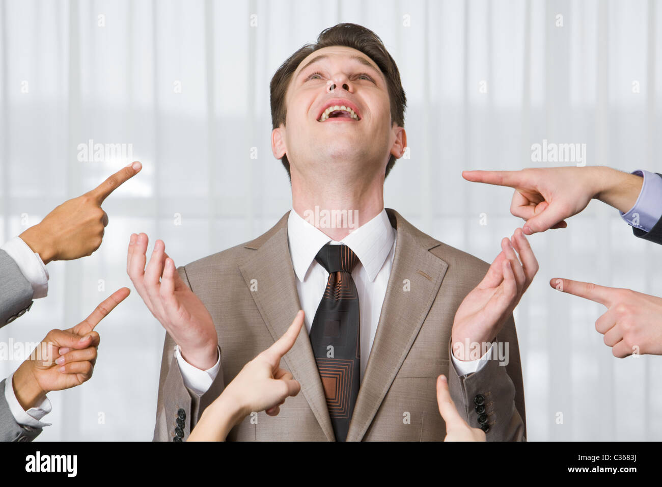 Inquiring businessman looking upwards surrounded by pointing hands ...