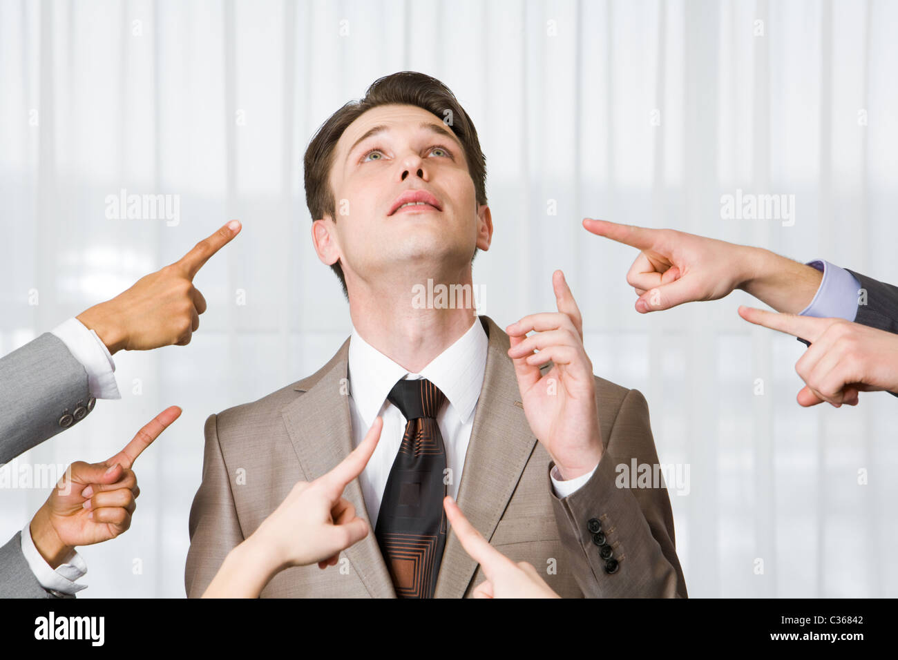 Inquiring businessman pointing upwards surrounded by several ...
