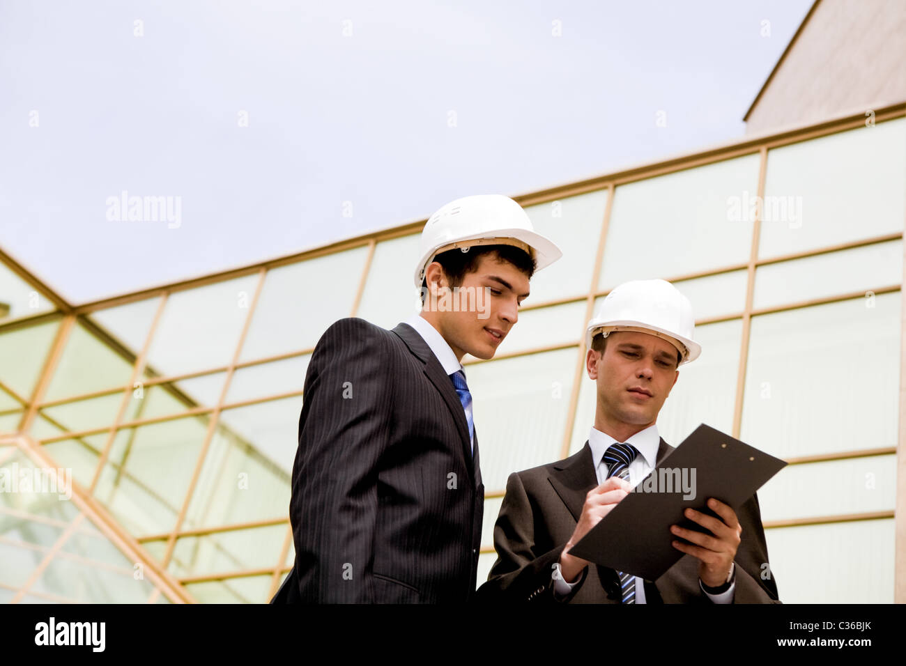 Photo of serious employees looking at document while planning work ...