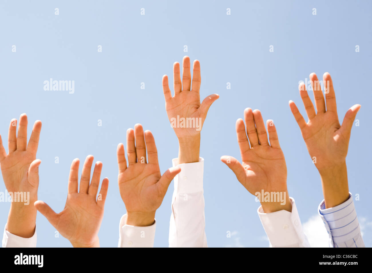 Close-up of several human hands raised against clear blue sky Stock ...