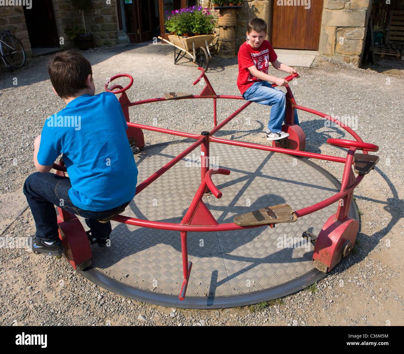 Children playing on Pedalled roundabout in Wray, Lancaster, UK Stock ...