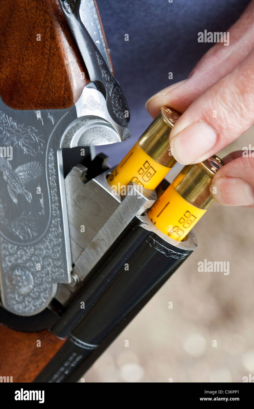 man loading cartridges into a over and under double barrel shotgun ...