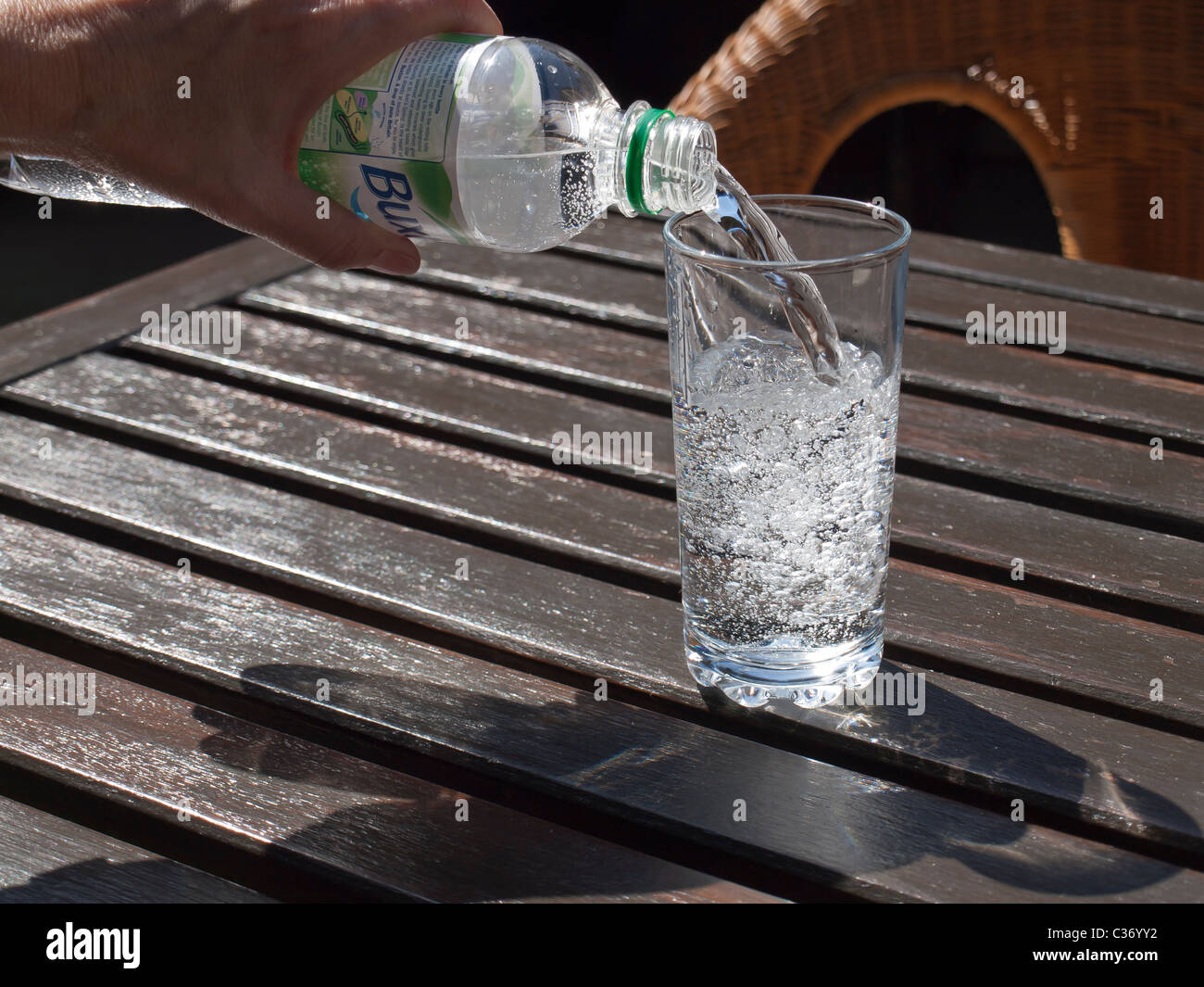 Pouring out a glass of mineral water from a plastic bottle on an ...