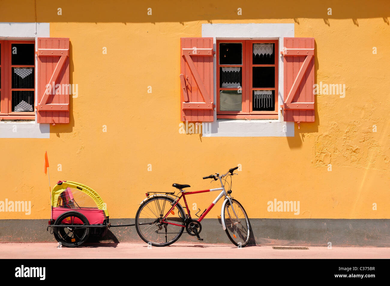 Bike pulling a stroller before an yellow-orange facade of a house in ...