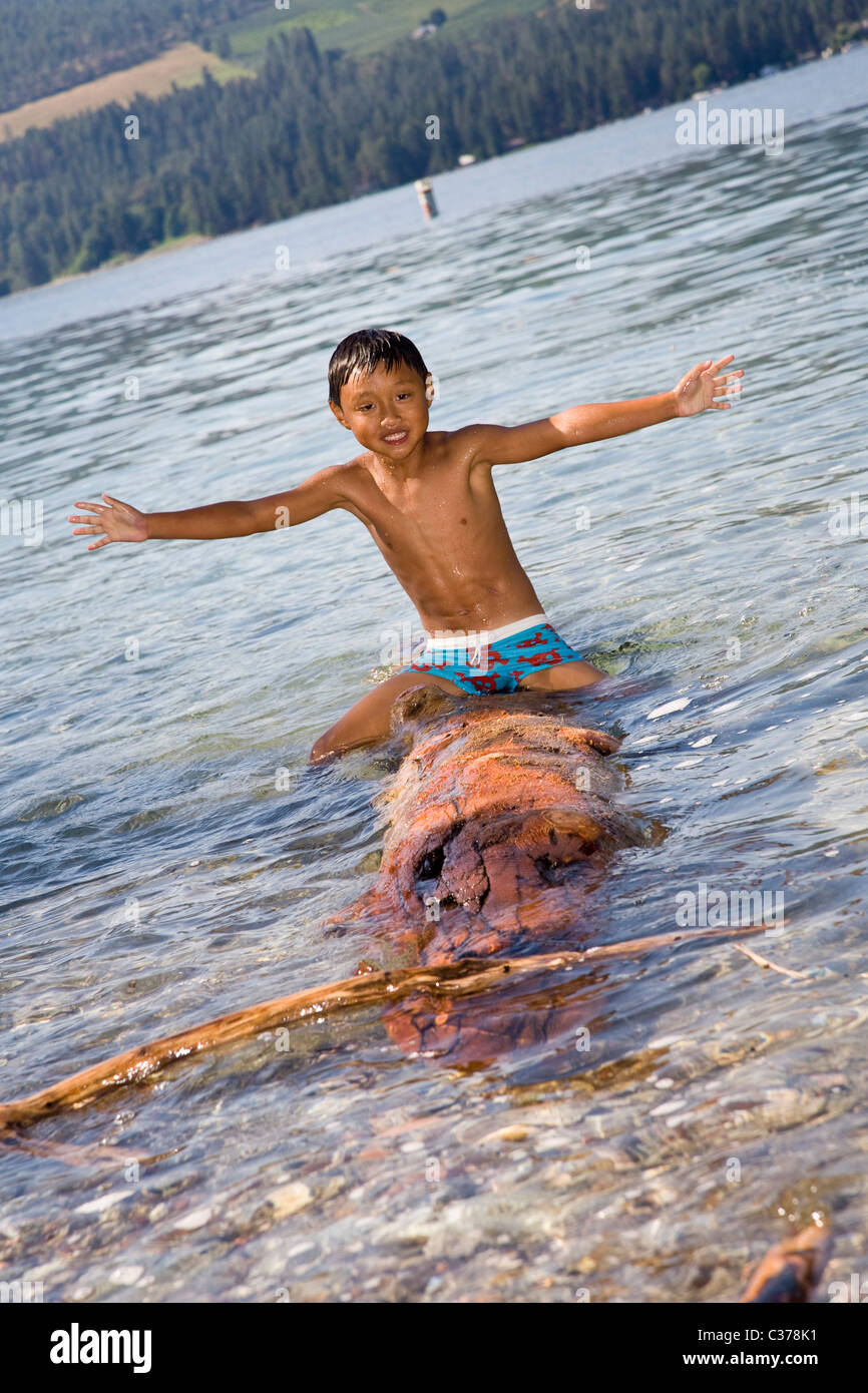 boy riding log in lake Stock Photo - Alamy