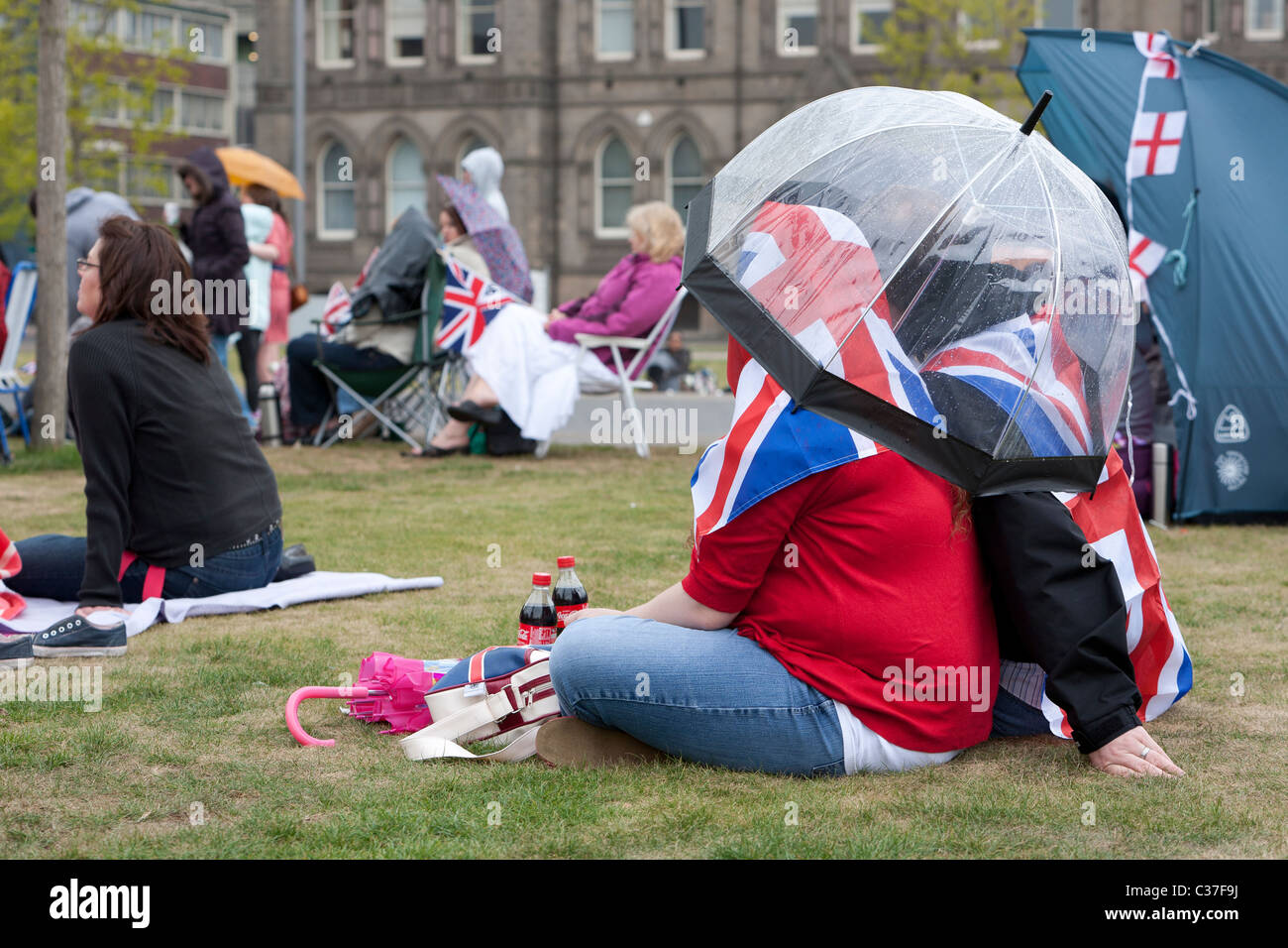 A couple, draped in the Union Jack, watch the Royal Wedding outdoors in ...