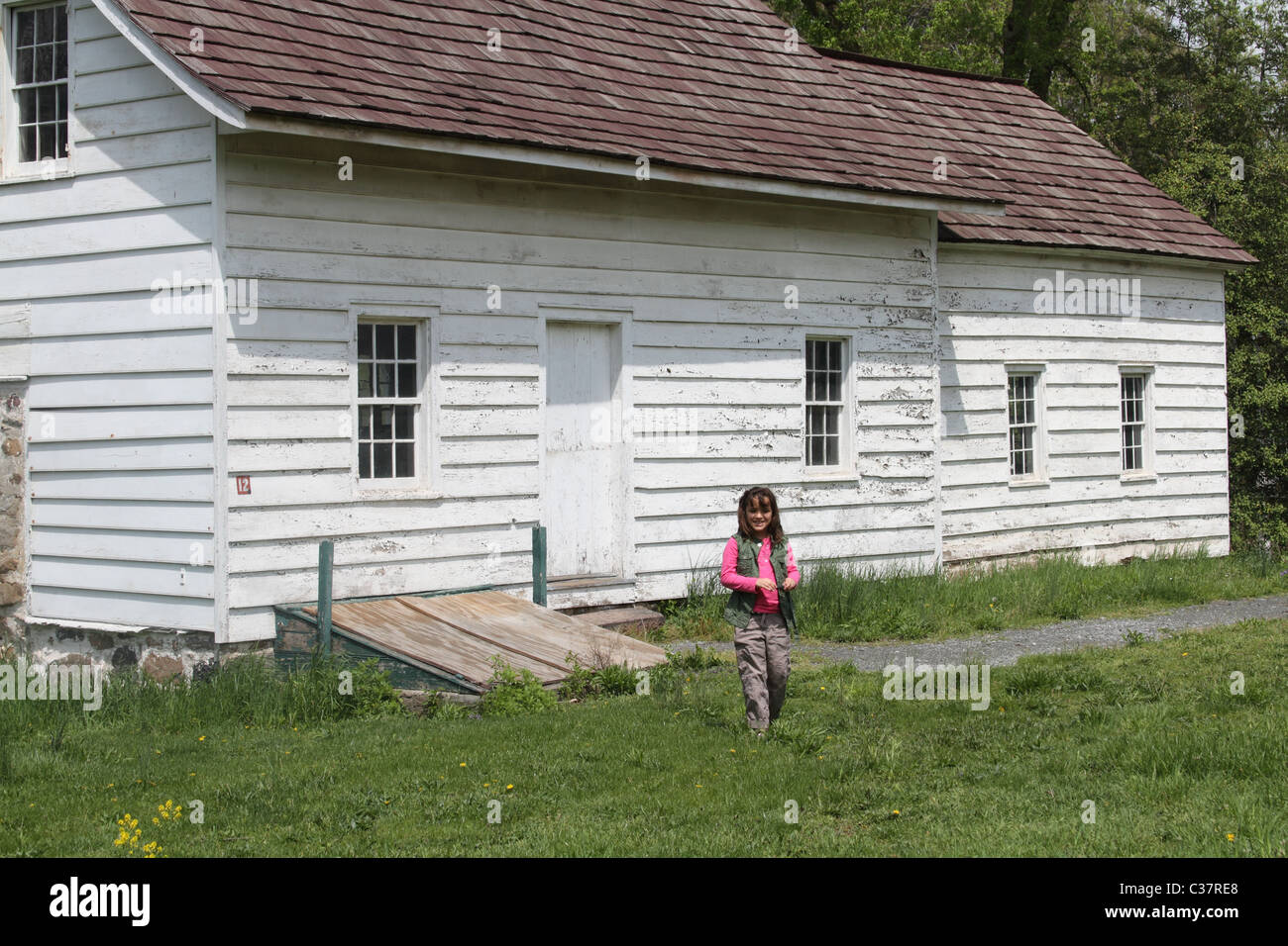 Young girl standing by old style White cottage Stock Photo - Alamy