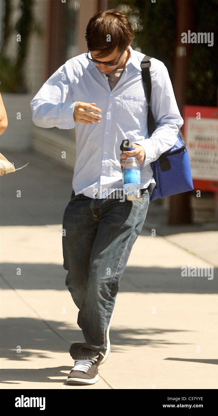 Tobey Maguire covers his face from photographers as he leaves Le Pain ...