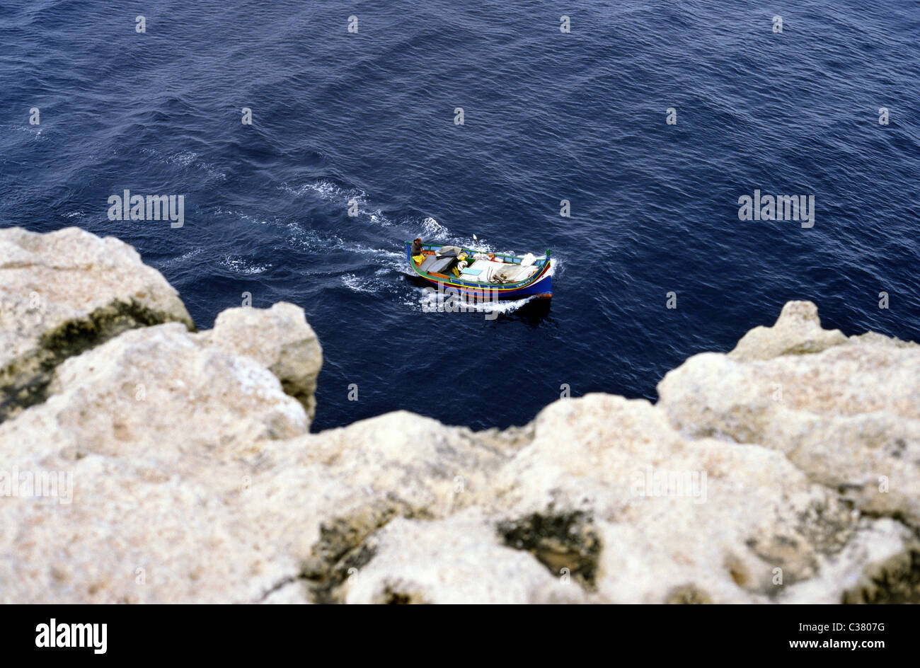 Traditional Luzzu fishing boat passing Pinu Point on the Maltese island ...