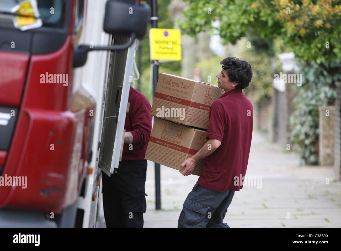 Movers are seen loading boxes and furnitures into a moving truck from ...