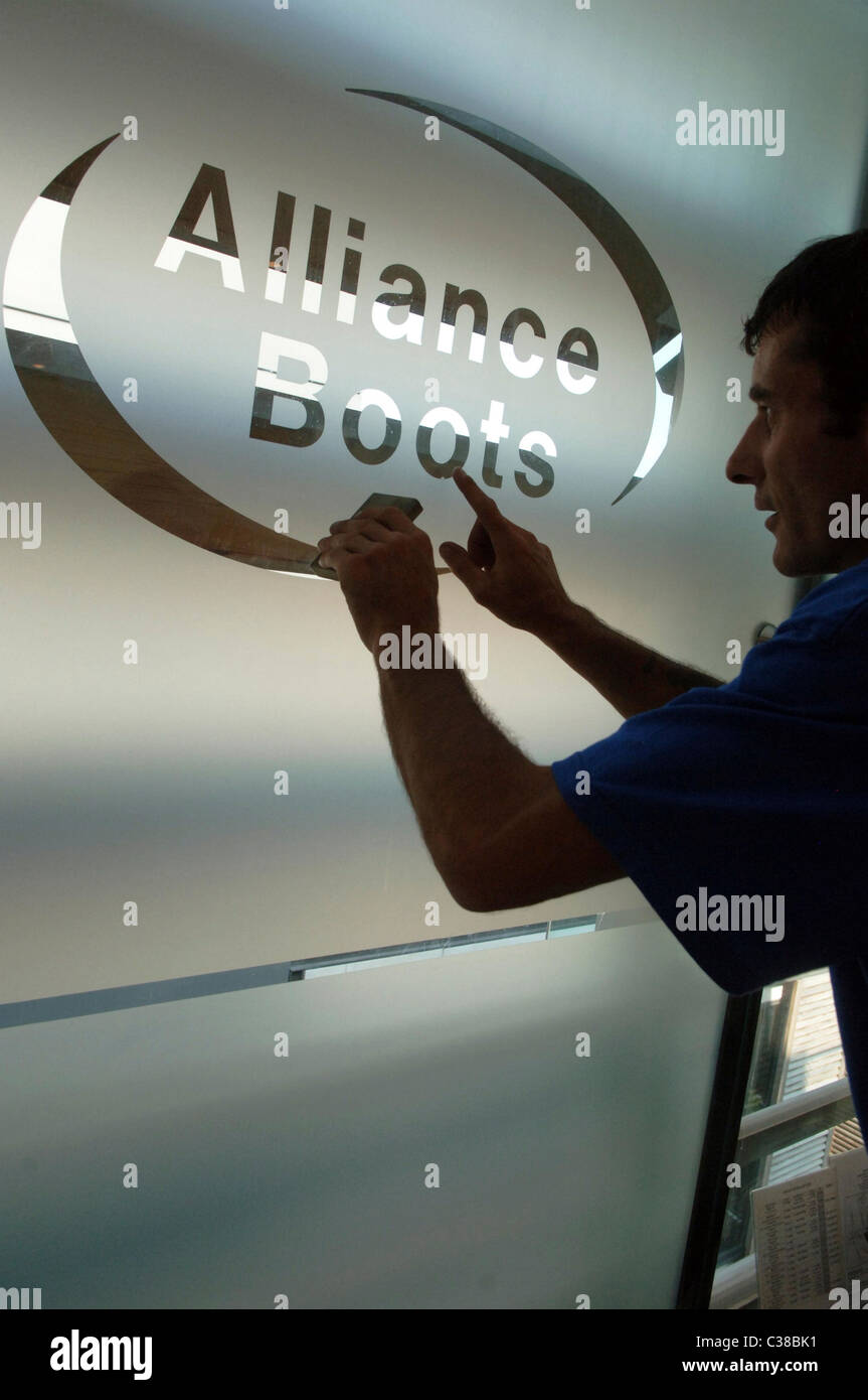 A worker cleaning an Alliance Boots frosted window logo Stock Photo - Alamy