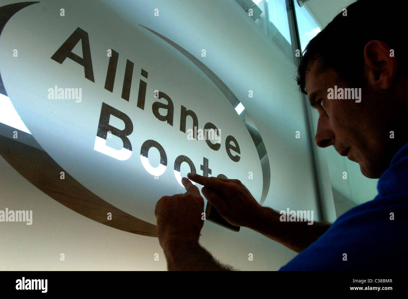 A worker cleaning an Alliance Boots frosted window logo Stock Photo - Alamy