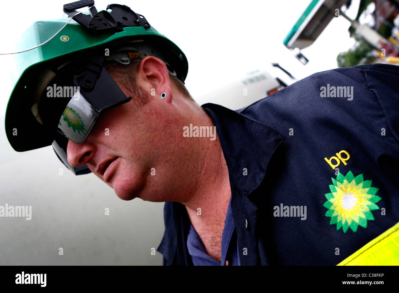 A BP employee in protective clothing (PPE) filling the pumps at a ...