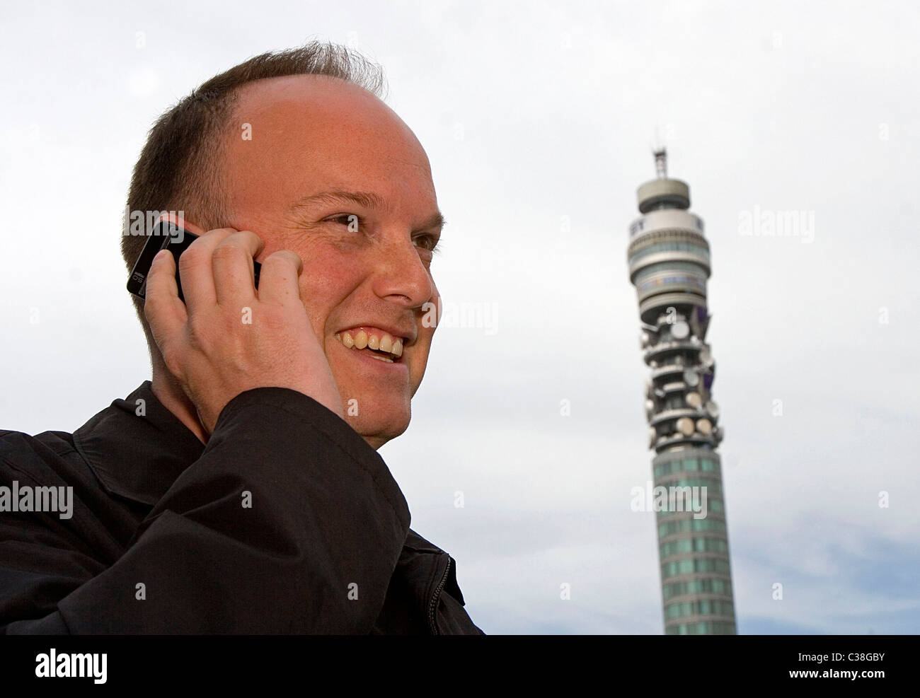 A man talks on his mobile while the BT Tower is visible in the ...