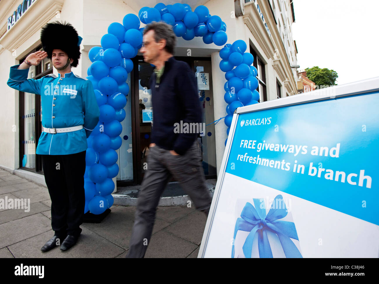 A person passes by a branch of Barclays bank, Cambridge. The guard is ...