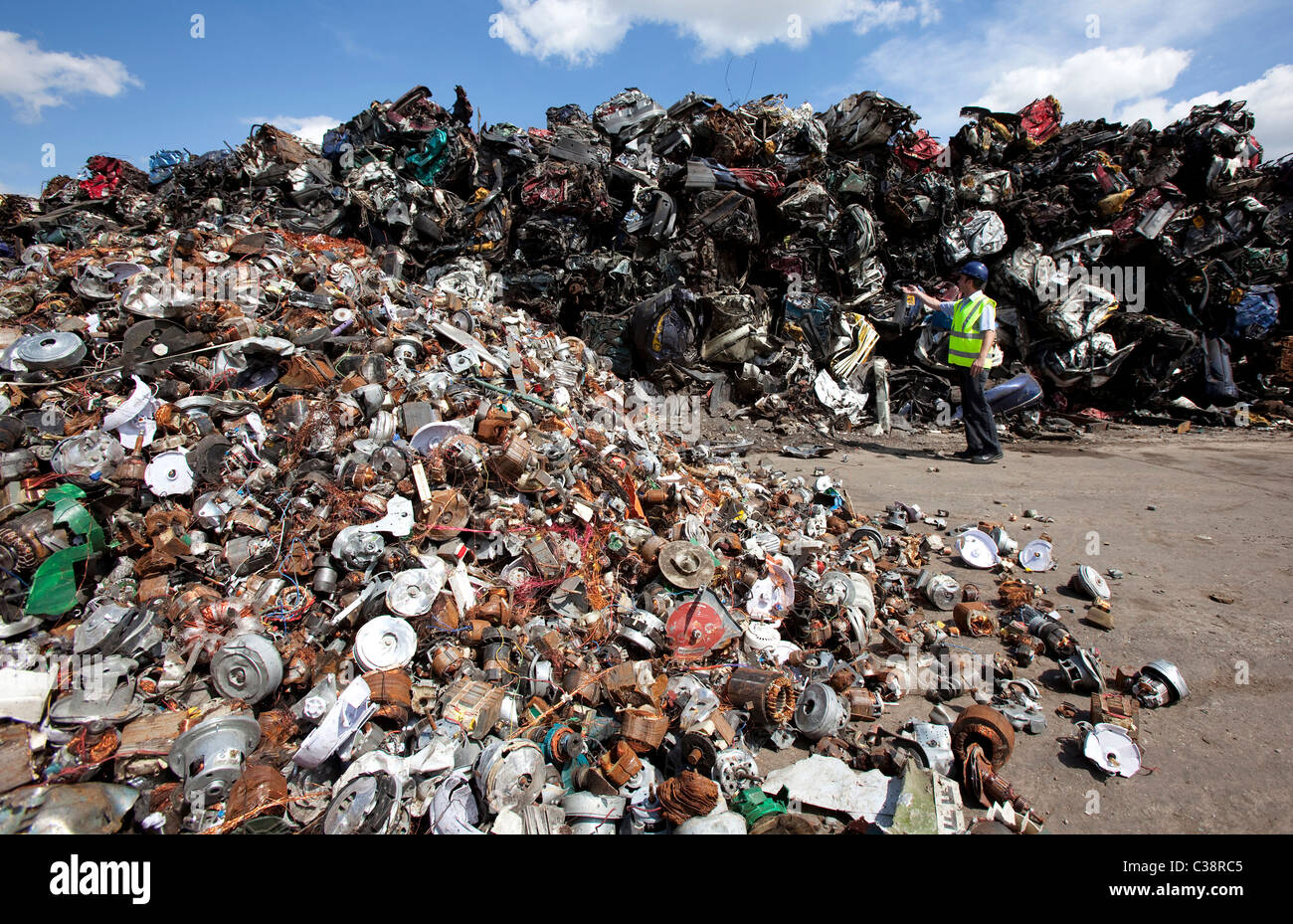 A scrapyard worker stands next to a pile of compacted cars Stock Photo ...