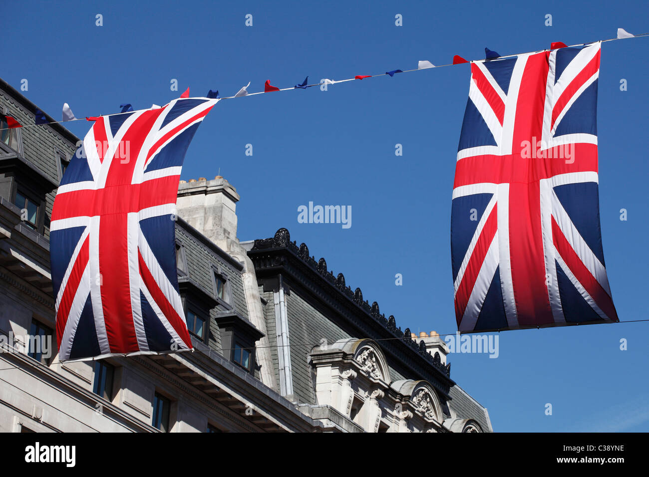 Two British "Union Jack" national flags flying against blue sky ...