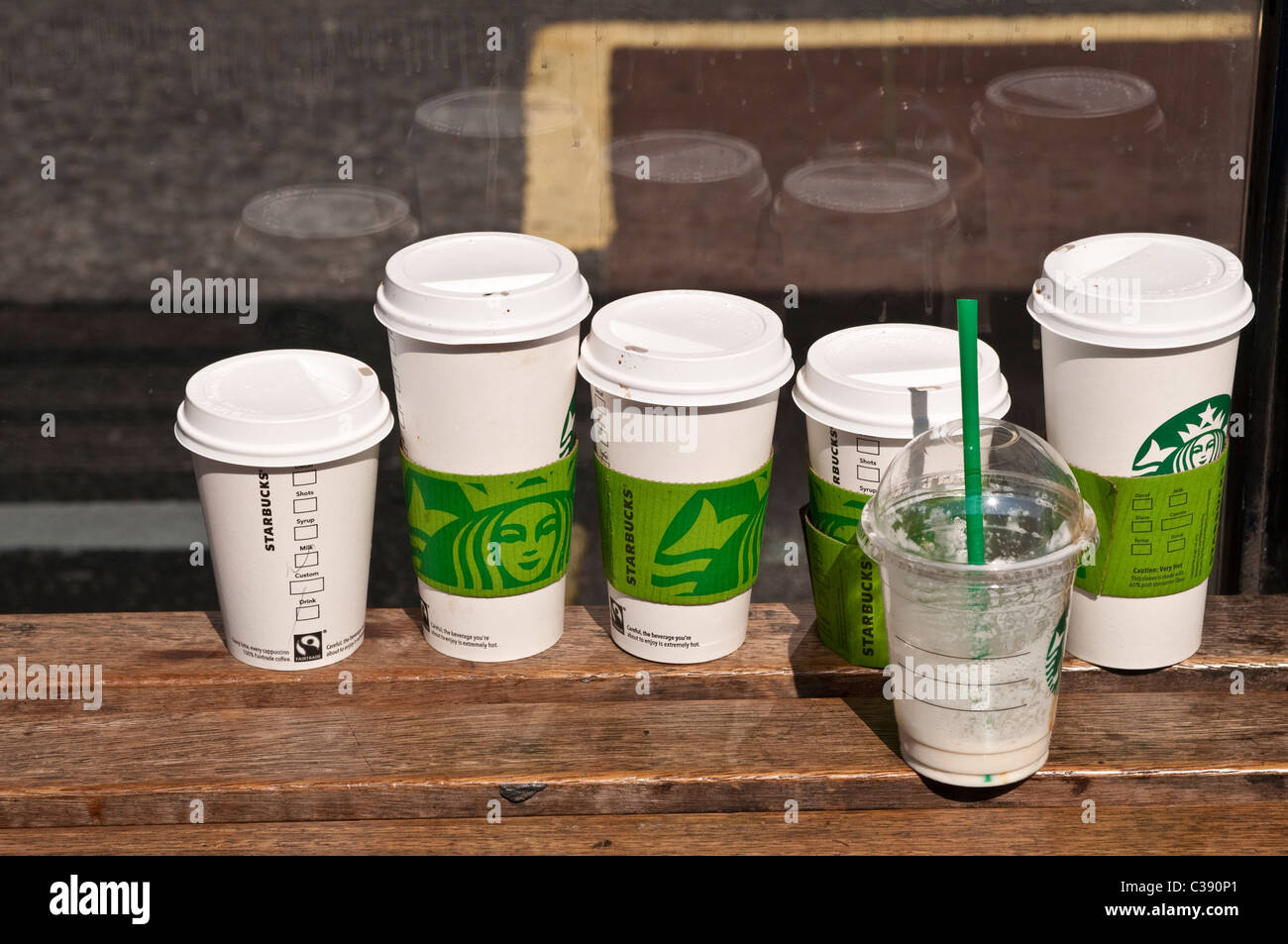 Neatly discarded plastic coffee cups on a bus stop bench, London, UK ...