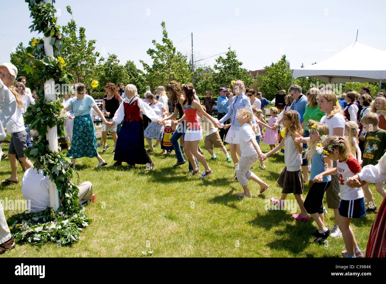 Group celebrating summer by circle dancing around the Maypole at the ...
