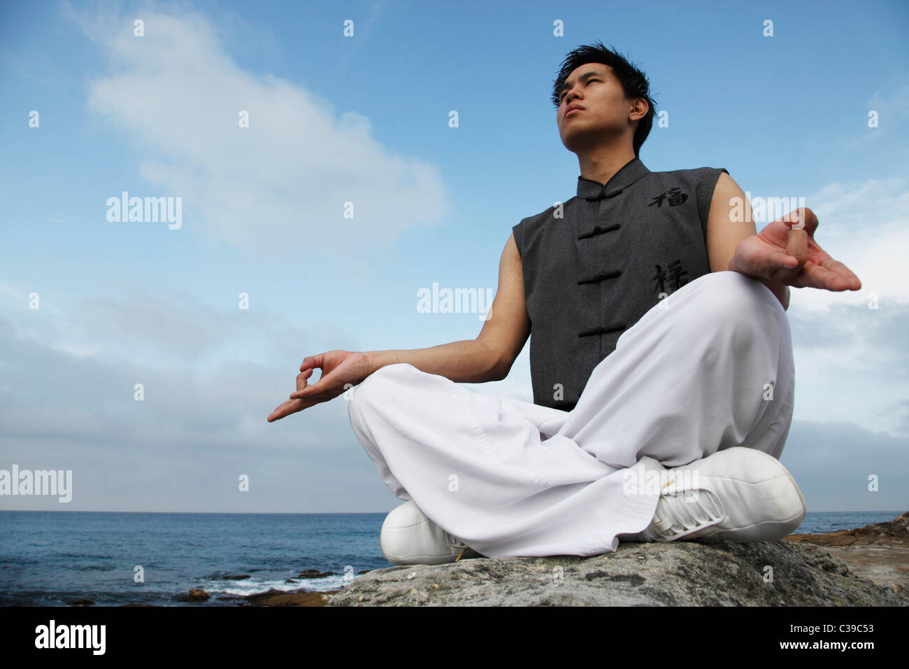 Chinese man meditating on rock Stock Photo - Alamy