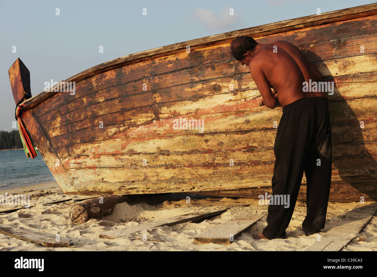 Asian man fixing boat on the beach Stock Photo - Alamy