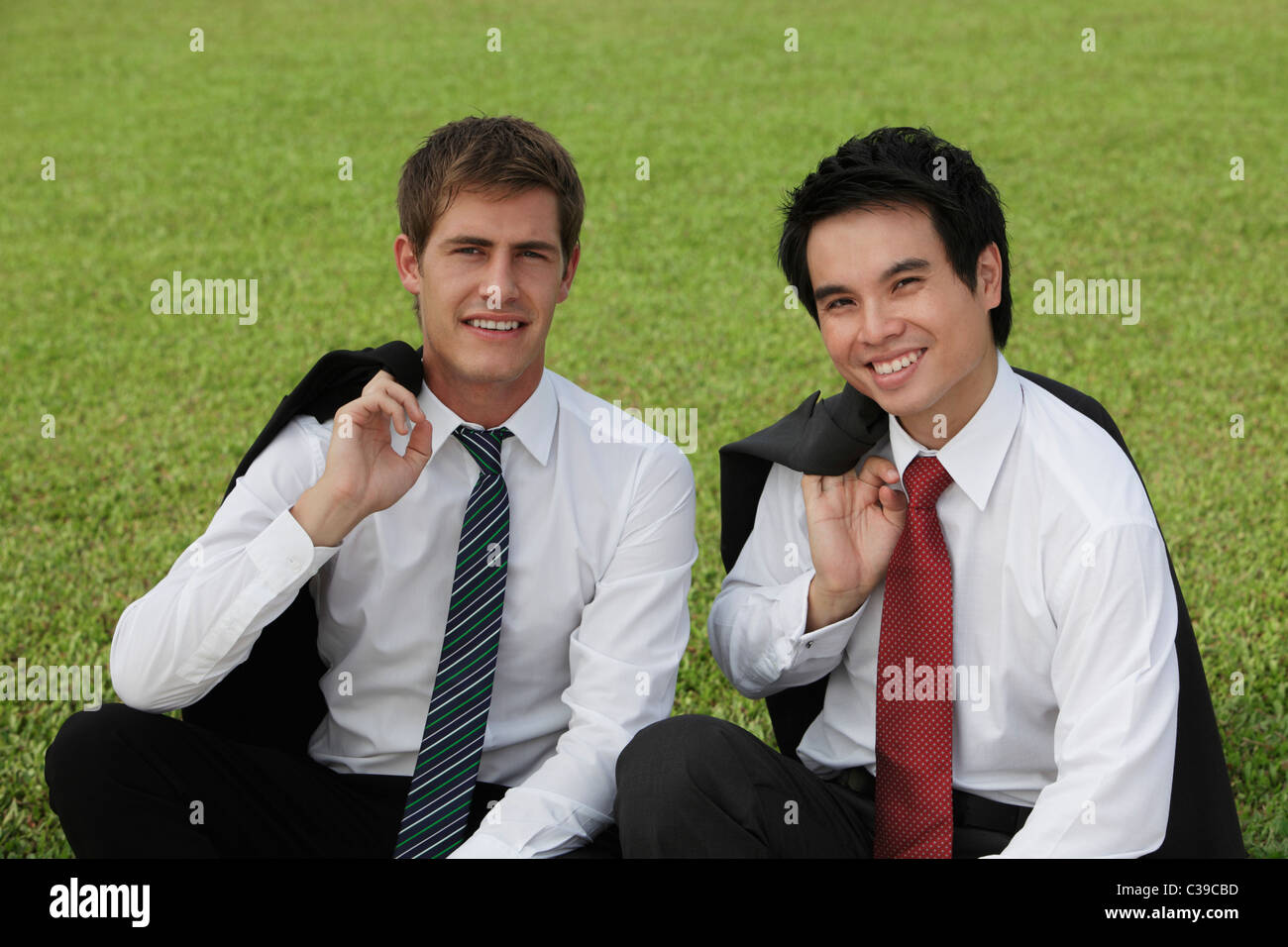 Chinese and Caucasian man sitting on grass with coats off Stock Photo ...
