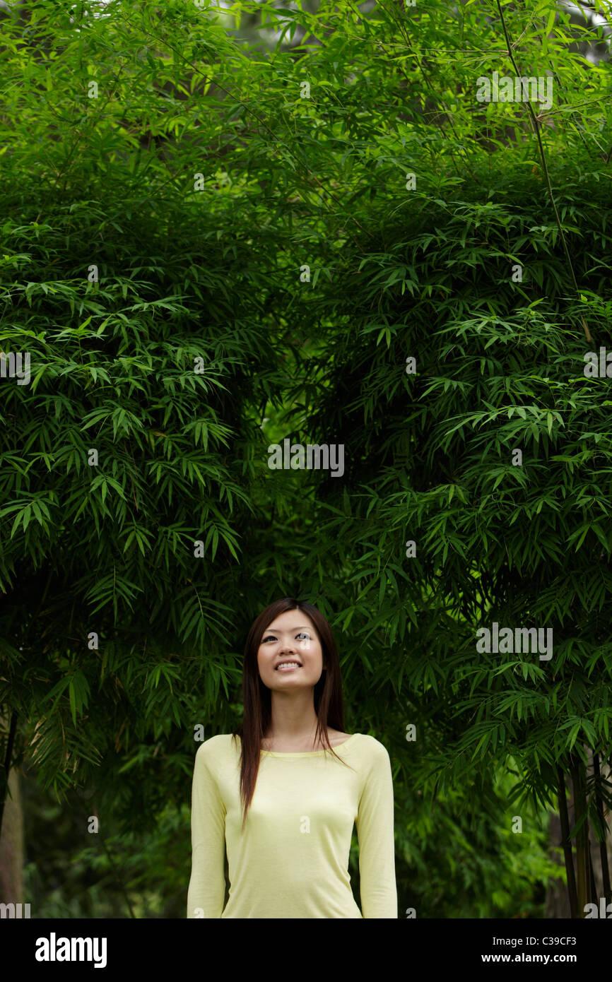 Young woman smiling in front of bamboo trees Stock Photo - Alamy